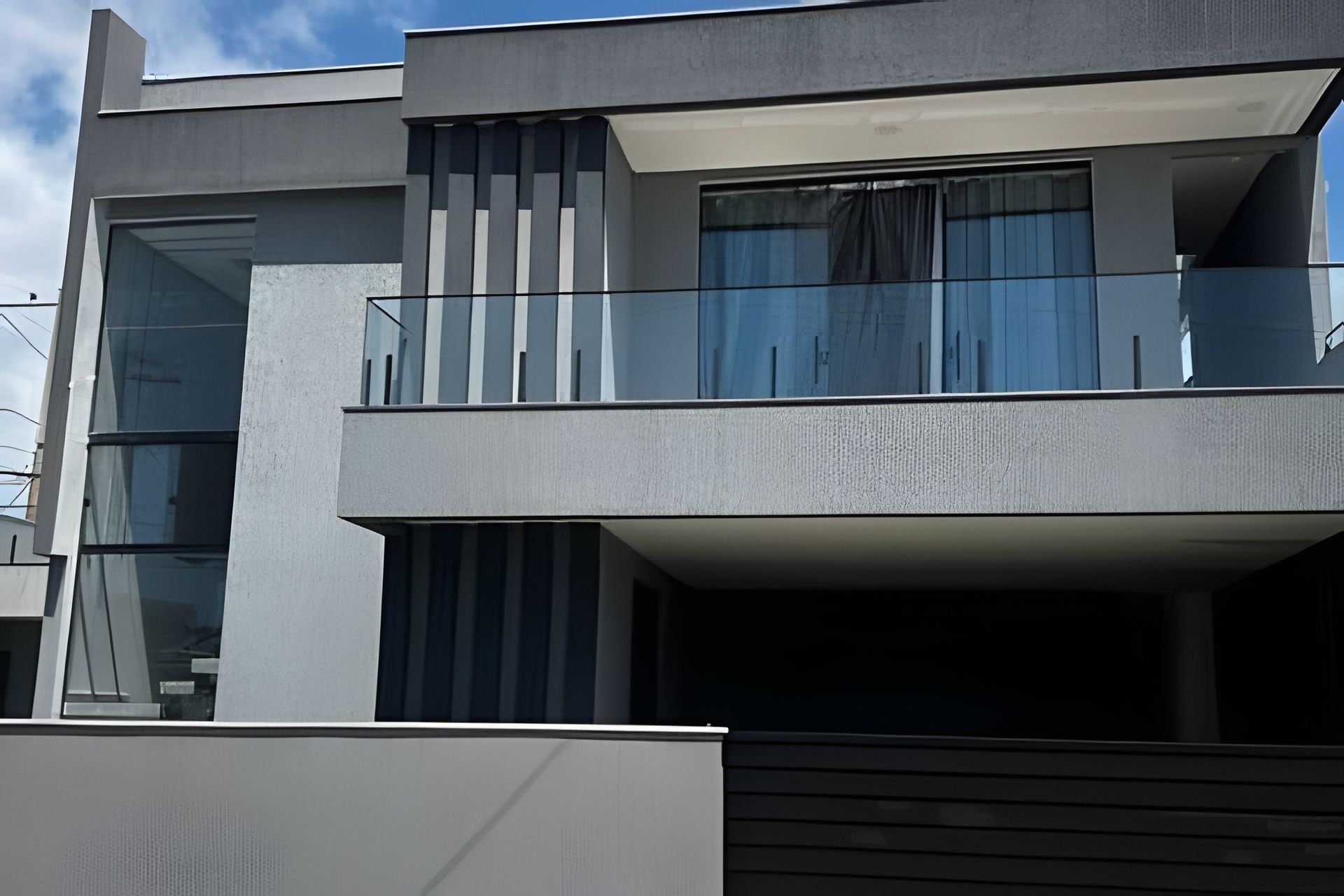 Um edifício moderno de vários andares, com grandes janelas e varanda.