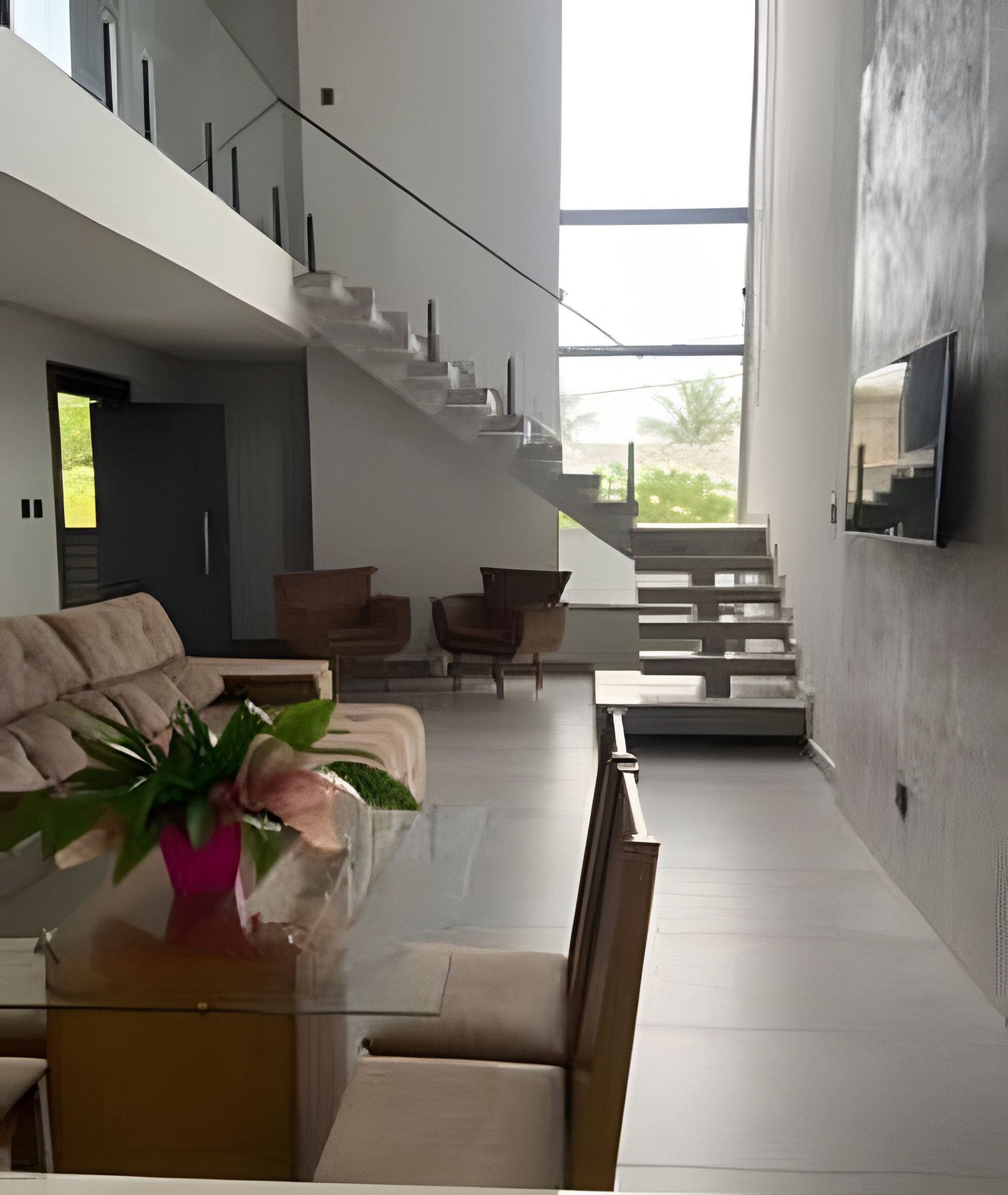 Um interior moderno com escada, sofá e televisão de tela plana na parede.