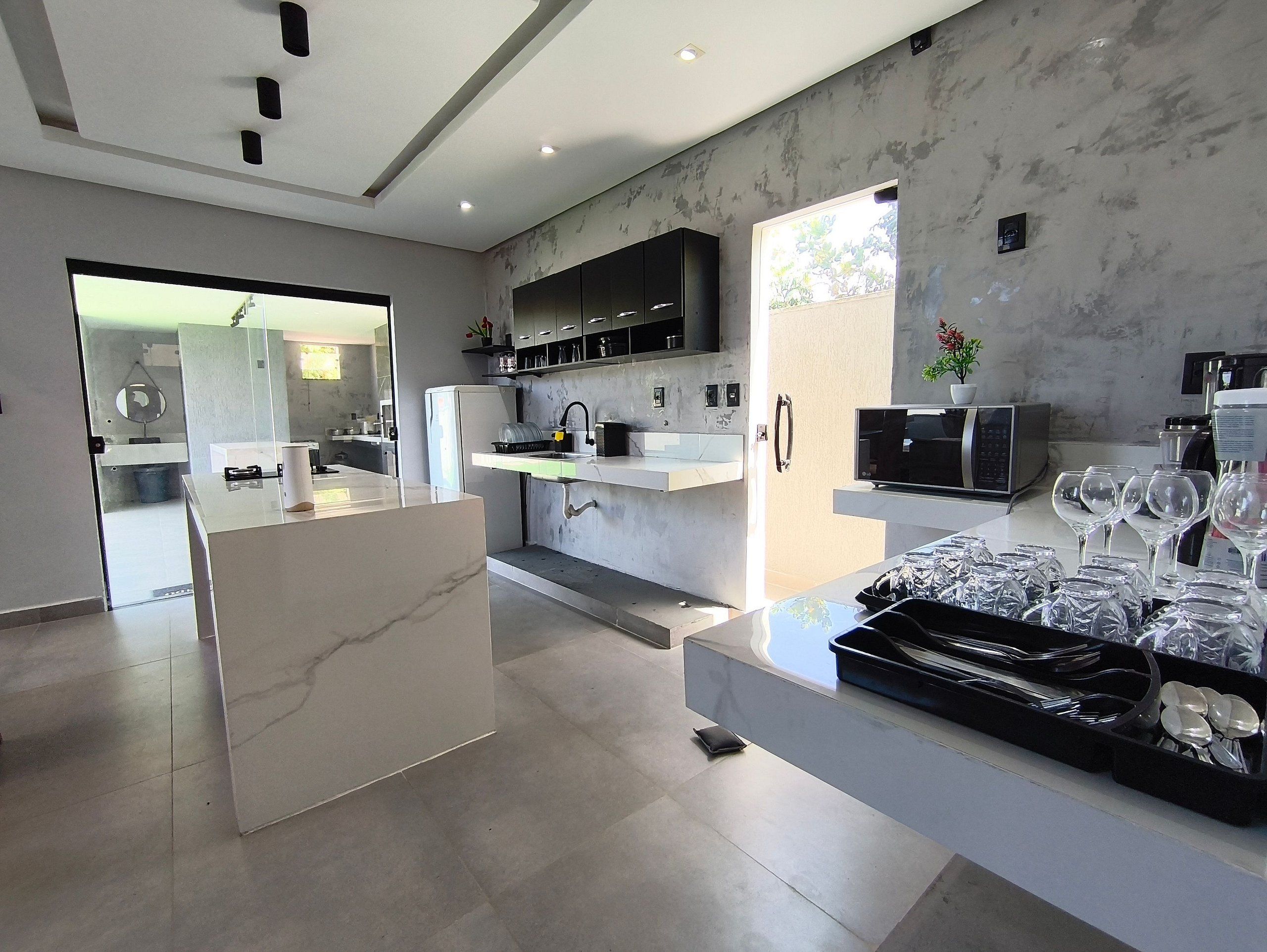 Cozinha moderna com bancada de mármore, eletrodomésticos embutidos e espaço para vinhos.