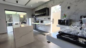 Cozinha moderna com bancada de mármore, eletrodomésticos embutidos e espaço para vinhos.