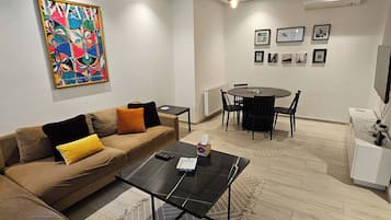 Uma sala de estar moderna com sofá, mesa de centro e área de jantar.