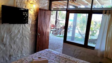Quarto com cama, televisão na parede e janela com cortinas.