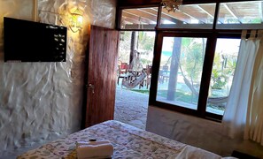 Quarto com cama, televisão na parede e janela com cortinas.