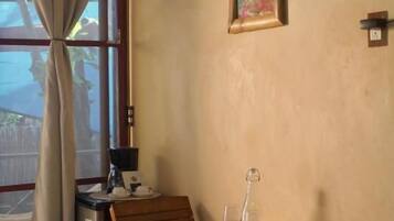 Quarto com mesa de jantar, cadeiras, geladeira, janela com cortinas e um quadro na parede.