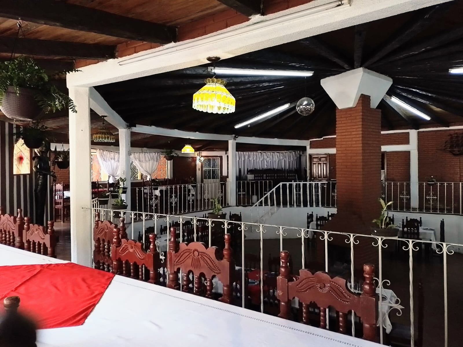 Amplo espaço interno com varanda, grades decorativas e plantas penduradas.