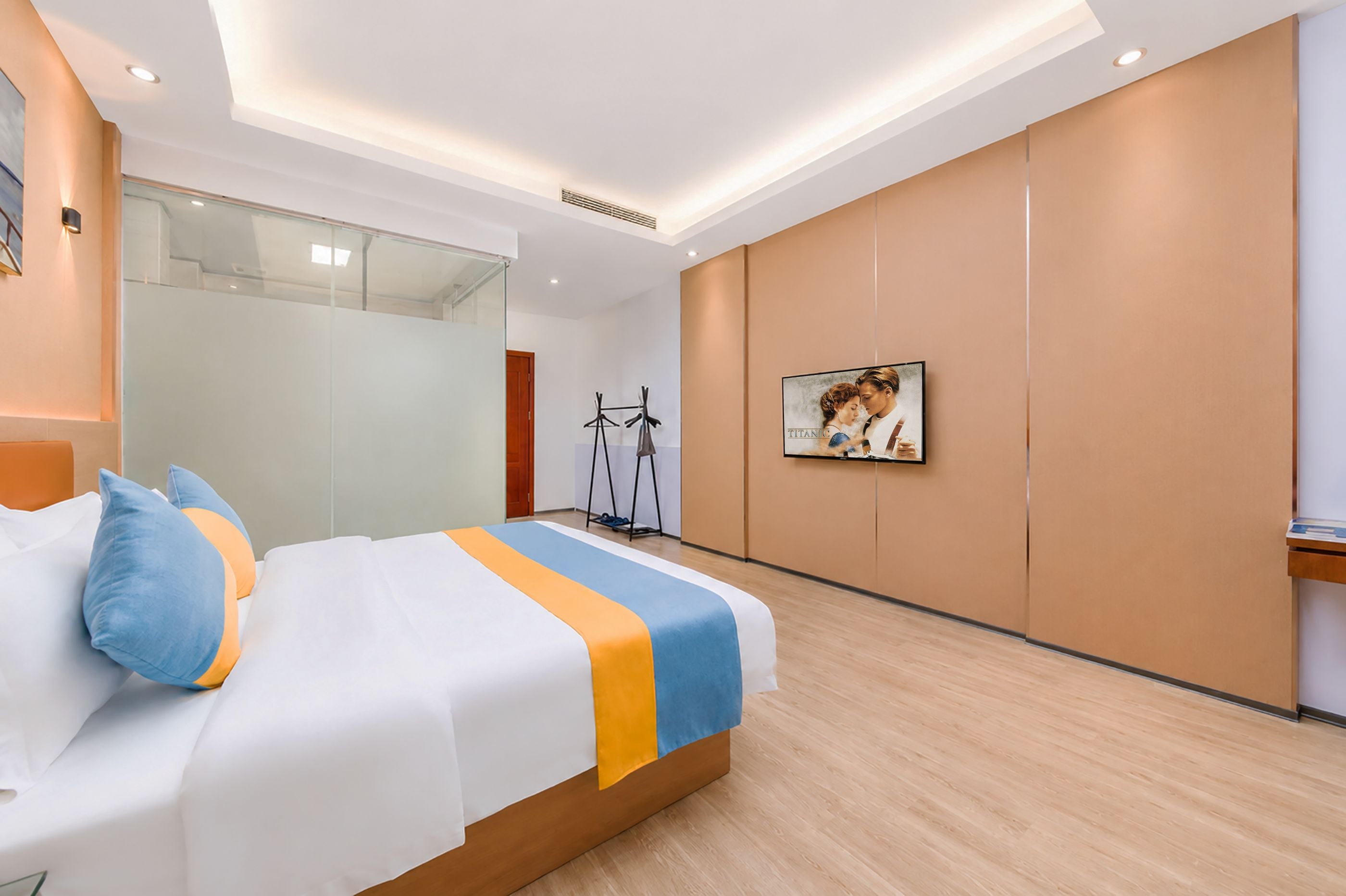 Quarto de hotel moderno com uma cama grande, televisão e divisória de vidro.