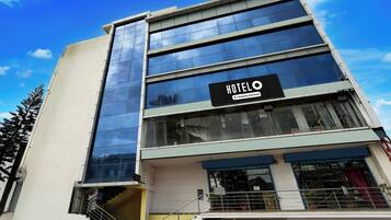 Um edifício moderno de hotel com uma placa grande que diz 'HOTEL', vários andares e uma escadaria que leva à entrada.