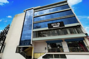 Um edifício moderno de hotel com uma placa grande que diz 'HOTEL', vários andares e uma escadaria que leva à entrada.