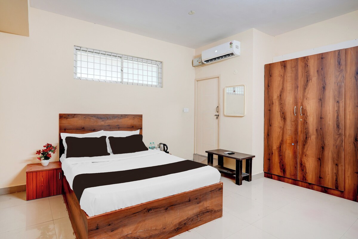 Quarto de hotel com cama de madeira, mesa de cabeceira pequena, guarda-roupa e ar condicionado.