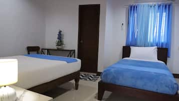 Quarto de hotel com duas camas, uma escrivaninha, uma cadeira, um vaso de plantas e uma janela com cortinas.