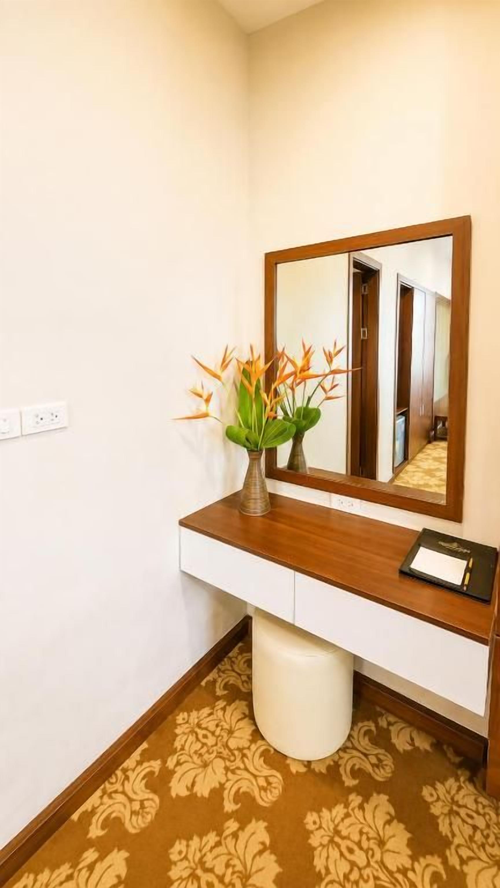 Casa de banho com toucador, espelho e um vaso com flores.