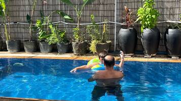 Piscina externa com cerca de bambu e plantas em vasos.