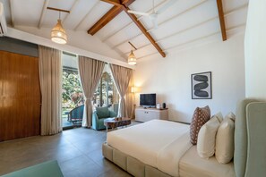 Quarto de hotel com cama, televisão, escrivaninha e vista para o exterior.