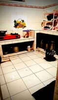 Cozinha com painel de azulejos, fogão por indução vermelho, pia e lixeira preta.