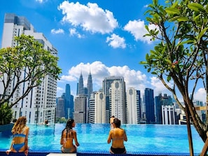 Piscina com vista para o horizonte urbano, incluindo edifícios altos e uma torre imponente.