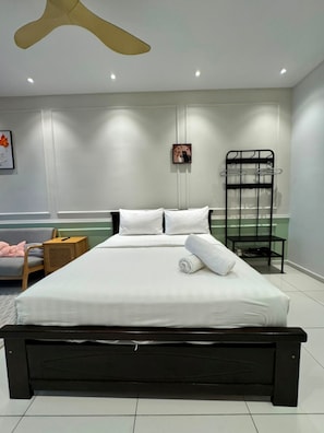 Uma cama bem arrumada com lençóis brancos, cabeceira de madeira e mesa de cabeceira de metal preto com prateleira de metal preto.