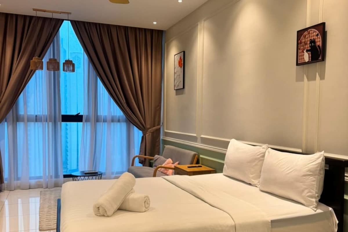 Quarto de hotel com cama grande, ventoinha no teto, janela com cortinas e quadro na parede.