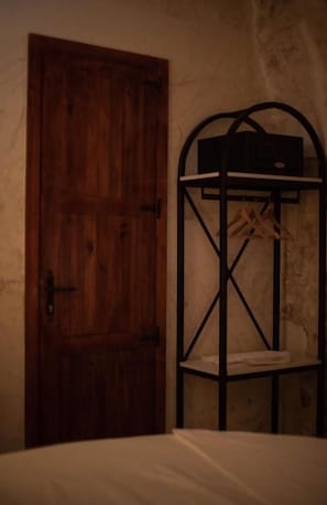 Quarto com porta de madeira, um porta-roupas de metal e uma cama.