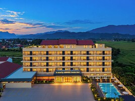 Um hotel com vários andares, piscina e vista para as montanhas.