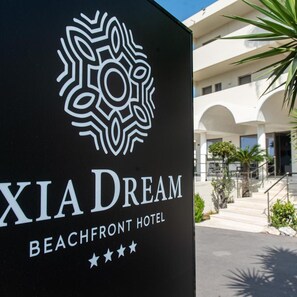 Placa do 'XIA DREAM BEACHFRONT HOTEL', com logotipo decorativo e quatro estrelas que indicam sua classificação.