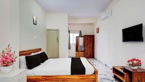 Quarto de hotel com cama, televisão na parede, guarda-roupa de madeira e chão de mármore.