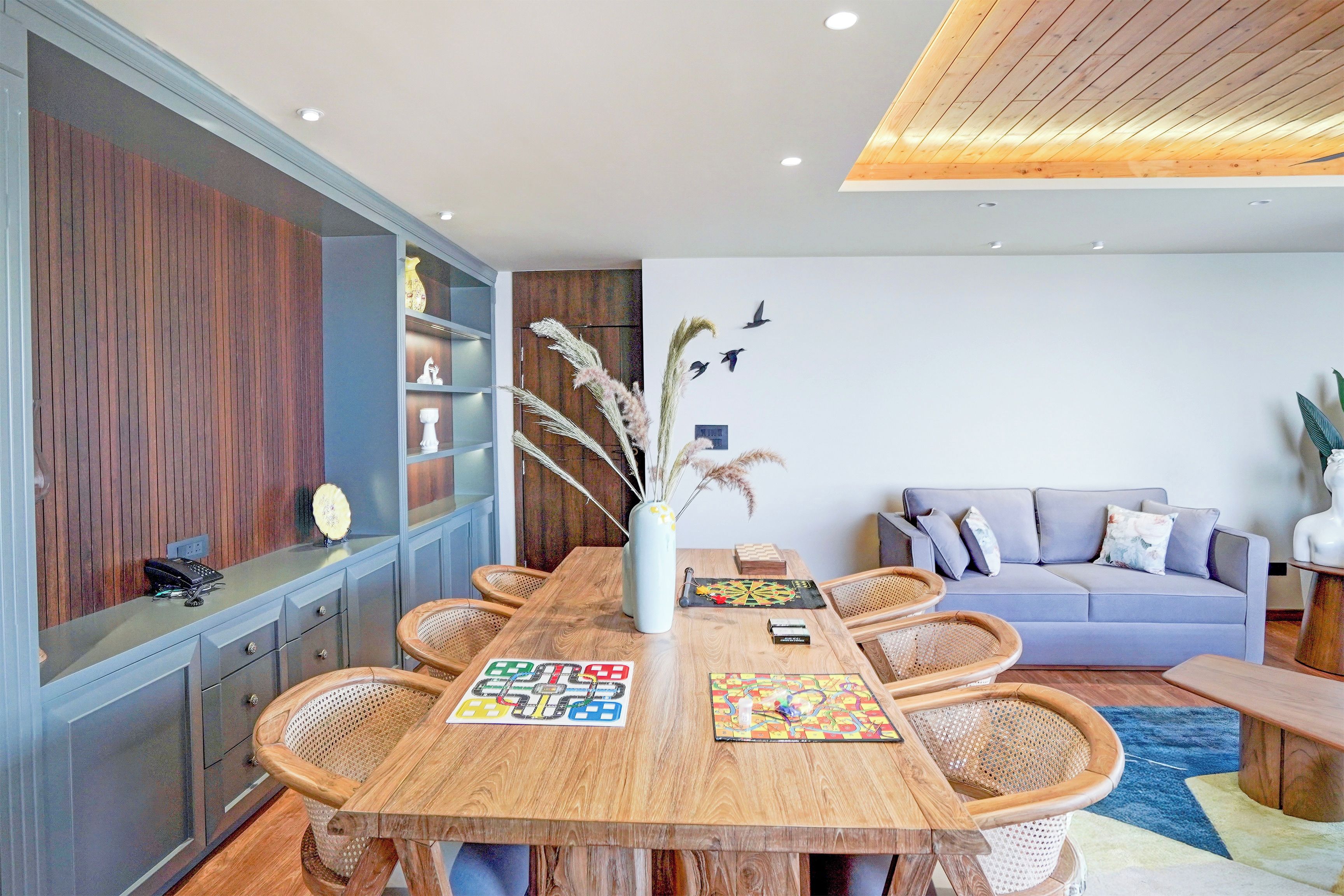 Uma sala de estar moderna com uma mesa de jantar de madeira, sofás e uma parede decorativa.