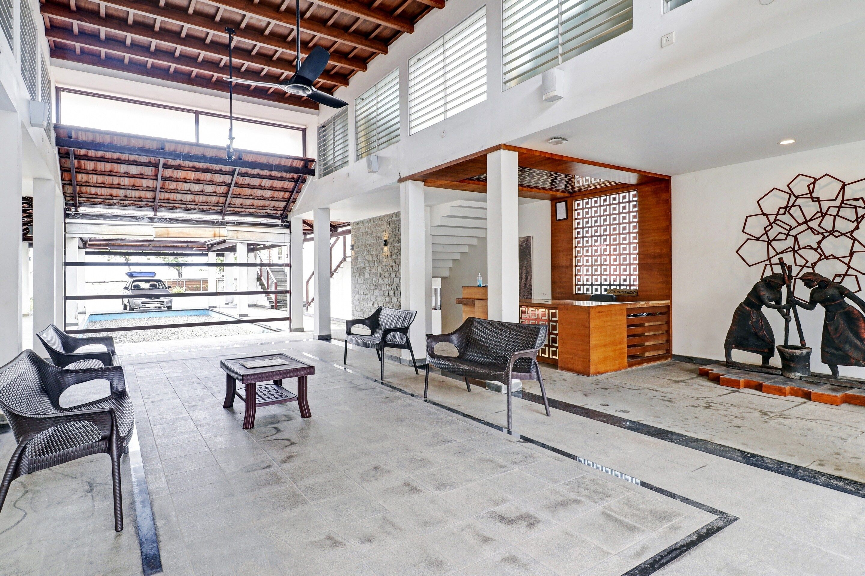 Um hall amplo com teto alto, balcão de recepção e área de estar com cadeiras e mesa.