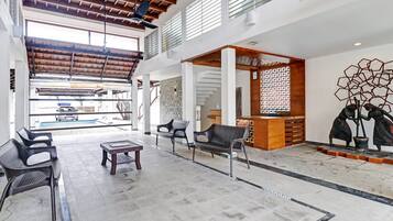 Um hall amplo com teto alto, balcão de recepção e área de estar com cadeiras e mesa.