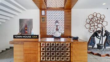 Uma mesa de recepção com um padrão geométrico, uma obra de arte emoldurada acima e uma estátua à direita.