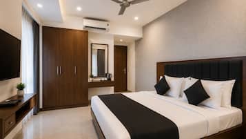 Quarto de hotel moderno com cama grande, guarda-roupa, TV de tela plana e ventoinha de teto.