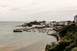 Uma vila costeira com um porto repleto de barcos, edifícios coloridos e um farol imponente.