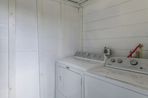 Uma lavanderia com duas máquinas de lavar e secar Maytag, uma mangueira vermelha e um painel de controle com diversas opções.