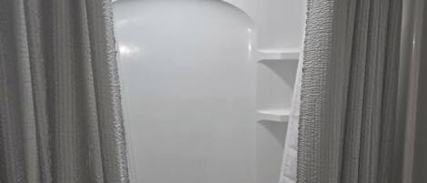 Área de duche com porta de vidro e barra de cortina de metal.