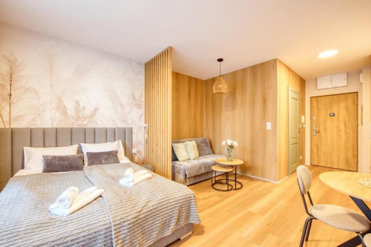 Quarto de hotel com uma cama grande, um sofá, uma mesinha redonda e uma cadeira.