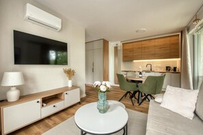Uma sala de estar moderna com uma televisão de tela plana, uma mesa de centro com um vaso de flores e um sofá.