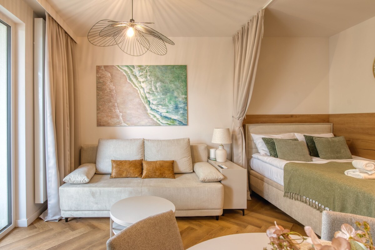 Quarto de hotel com sofá, cama, mesa e um quadro na parede.