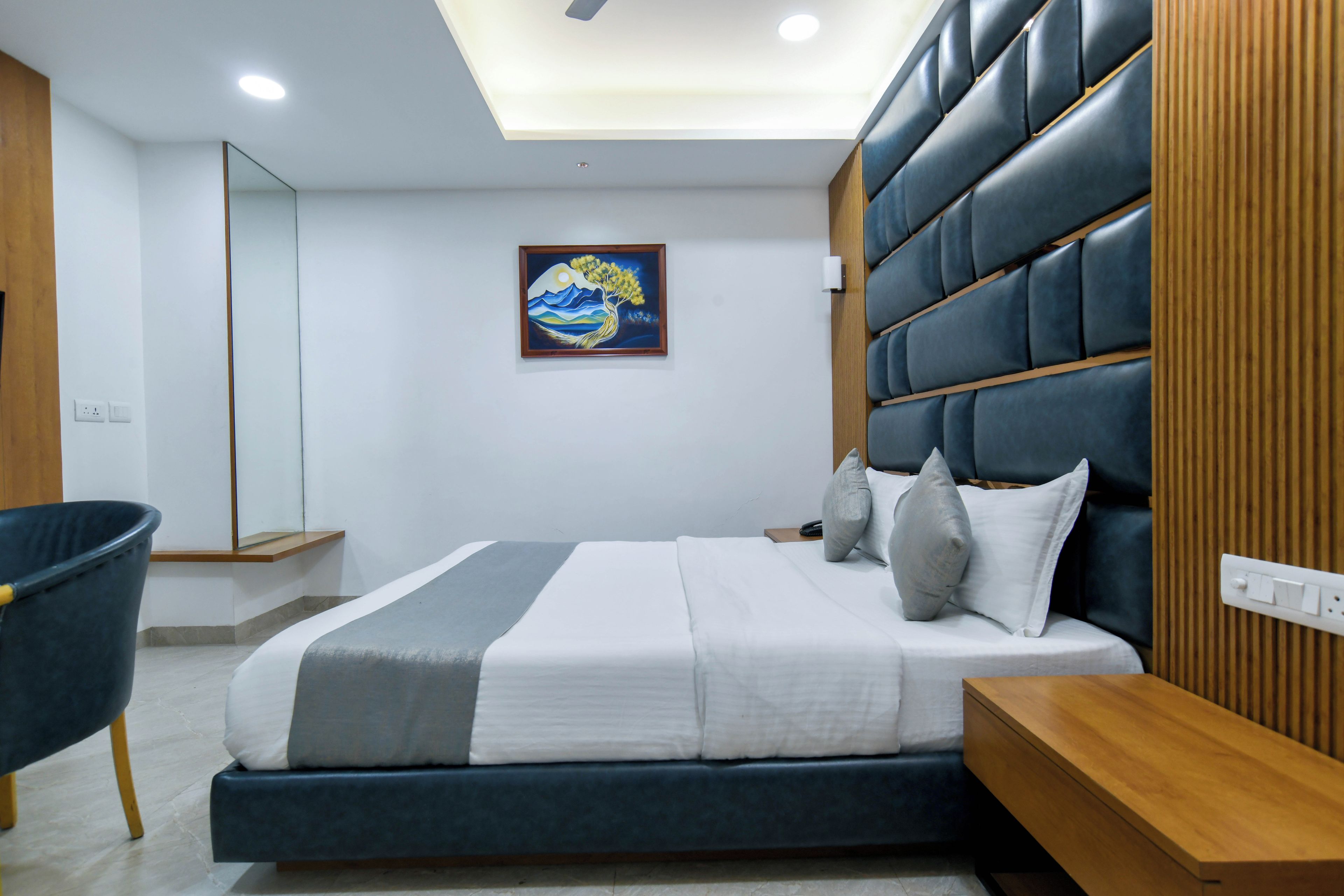 Quarto moderno com cama, mesa de cabeceira e uma cadeira.