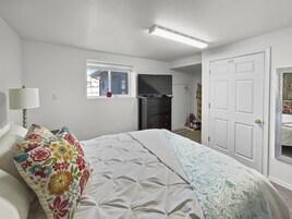 Quarto com cama, cômoda, televisão e janela.