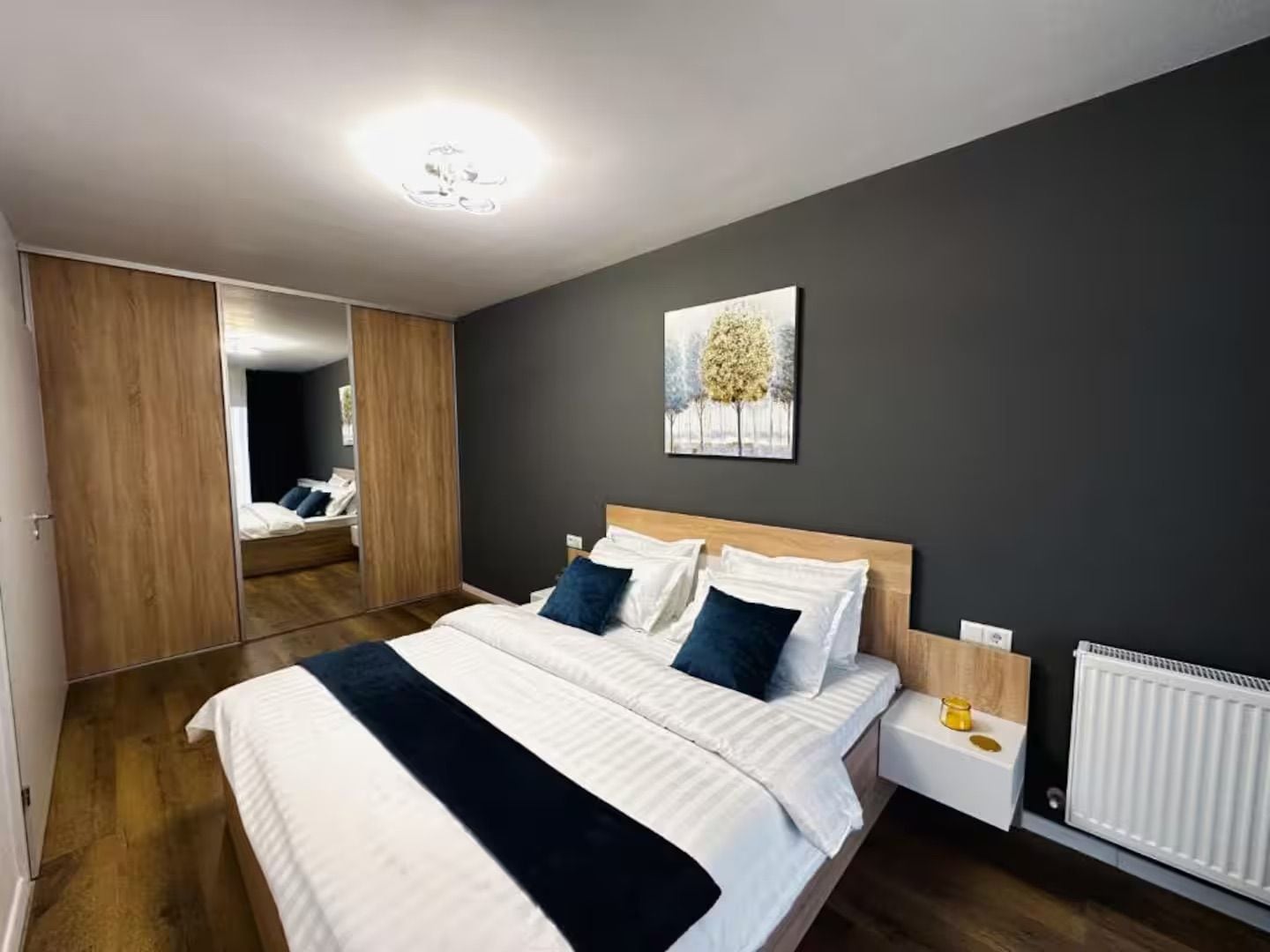 Quarto com cama, mesa de cabeceira e radiador.