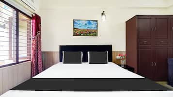 Quarto de hotel com cama, mesa de cabeceira, pintura e guarda-roupa.