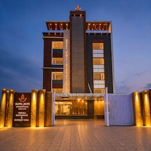 Um edifício moderno de hotel com entrada destacada, sinalização iluminada e fachada bem iluminada.