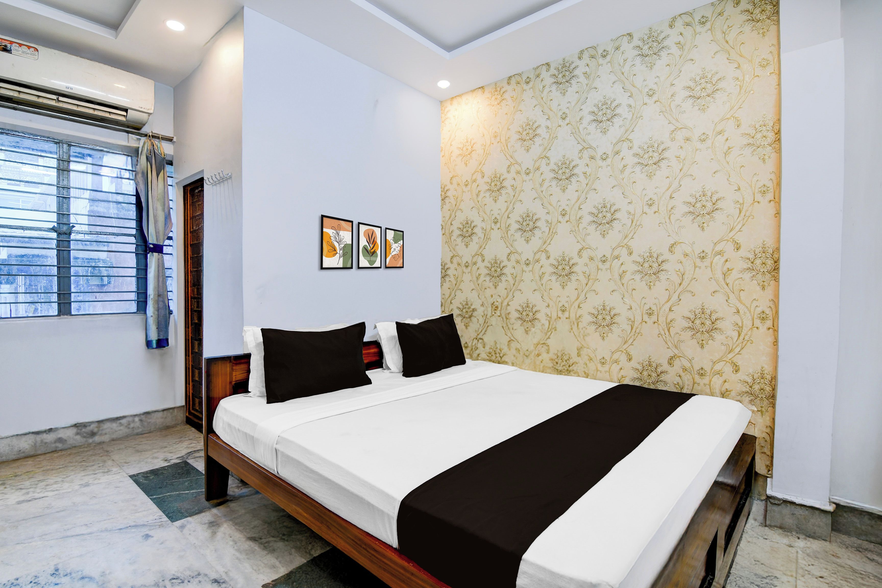 Quarto de hotel com cama, janela com cortinas, parede com padrão floral e teto com iluminação embutida.
