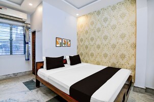 Quarto de hotel com cama, janela com cortinas, parede com padrão floral e teto com iluminação embutida.