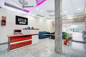 Uma área de recepção de hotel com um balcão, um sofá azul e um ventilador de teto.
