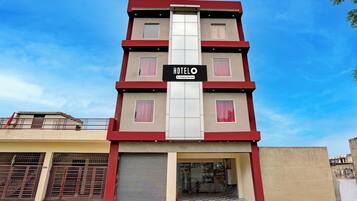 Um hotel com vários andares e uma placa chamativa com a palavra 'HOTELO' e um símbolo da marca.