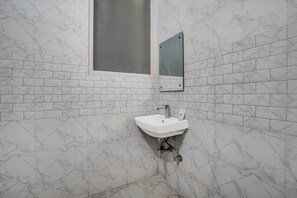 Casa de banho com lavatório branco, espelho e janela.