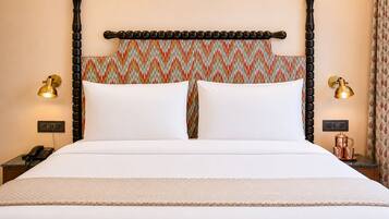 Quarto de hotel com cama de dossel, duas luminárias de cabeceira, telefone e painel decorativo na parede.