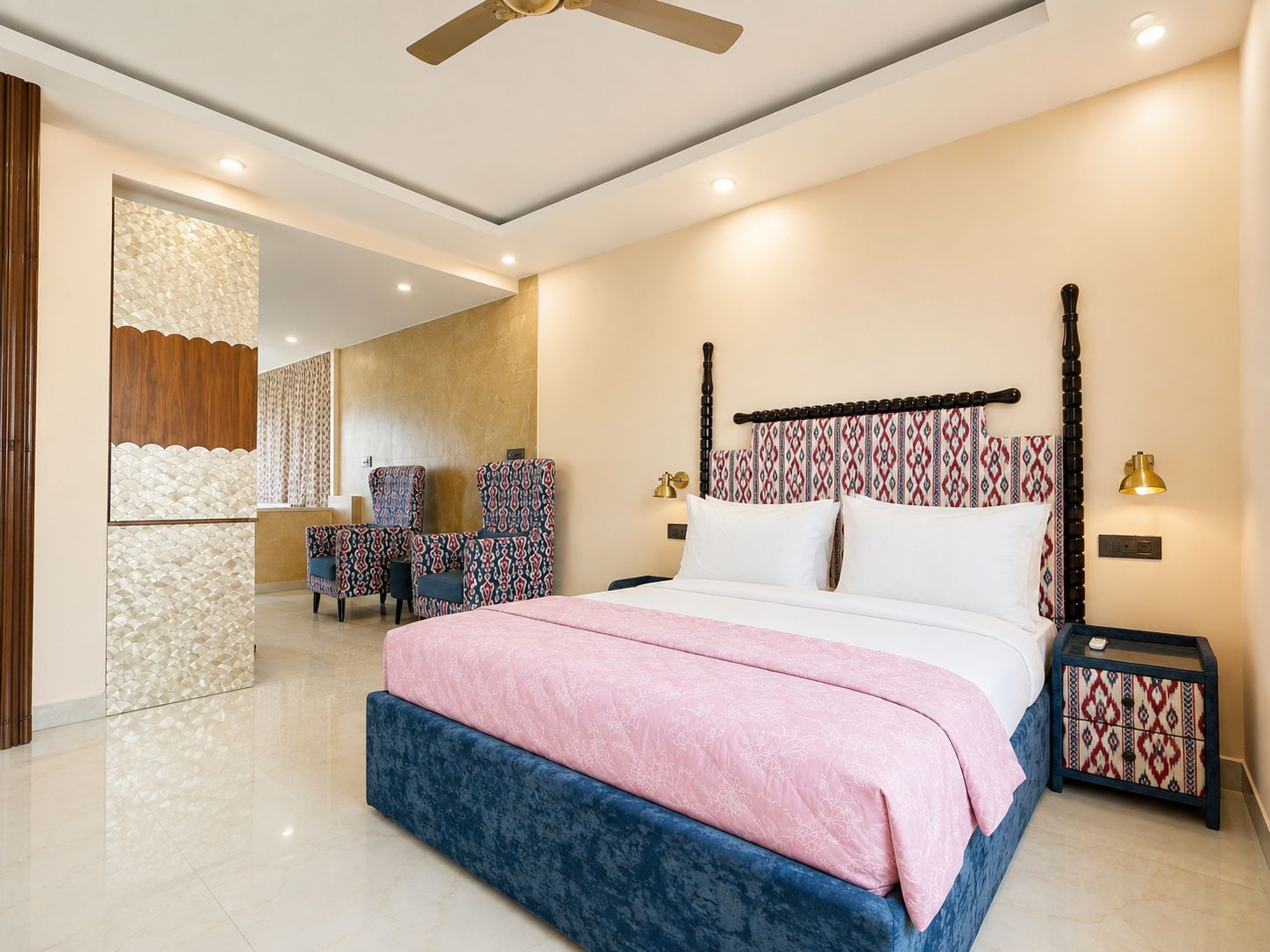 Quarto de hotel moderno com uma cama grande, uma escrivaninha, duas cadeiras, um espelho e um ventilador de teto.