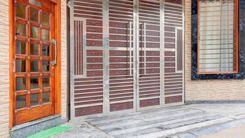 Entrada de um edifício com porta de recepção, um grande portão de metal e uma janela com cortina.