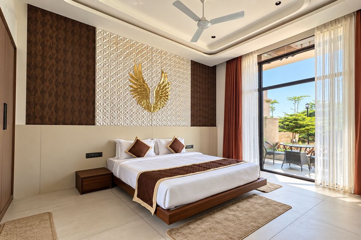 Quarto moderno com uma cama grande, ventilador de teto e vista para o exterior através de uma porta de vidro.